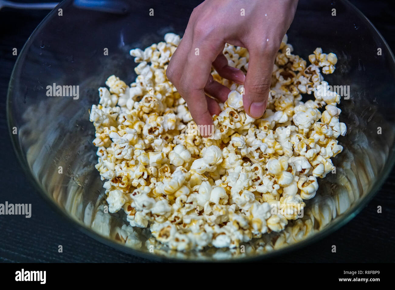 top view of hand grabbing popcorn from bowl Stock Photo - Alamy