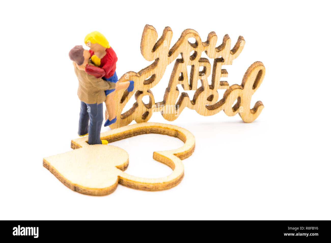 Miniature figures as in love hugging couple next to You Are Loved ...