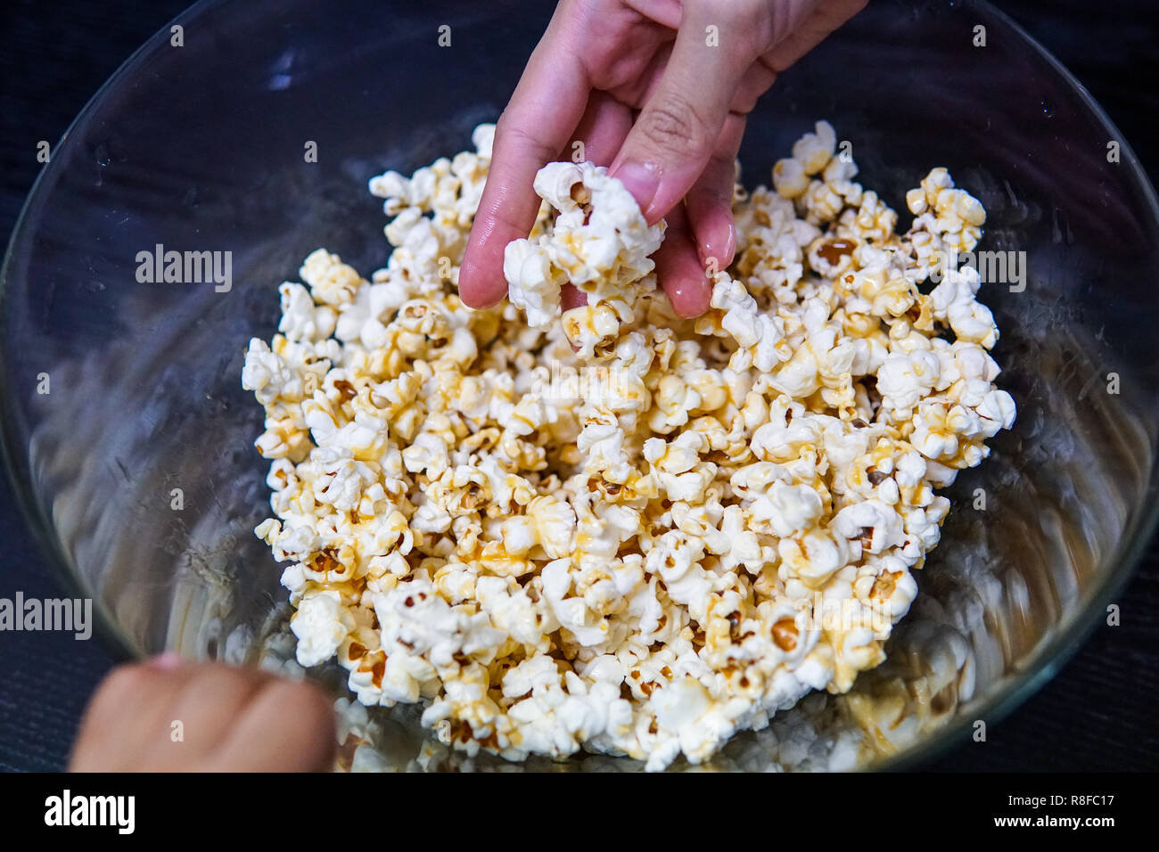 top view of hand grabbing popcorn from bowl Stock Photo - Alamy