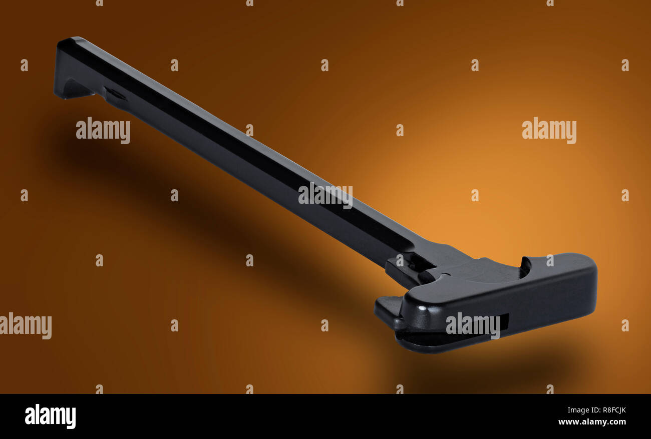 Charging handle for an assault rifle on a brown background with shadow ...