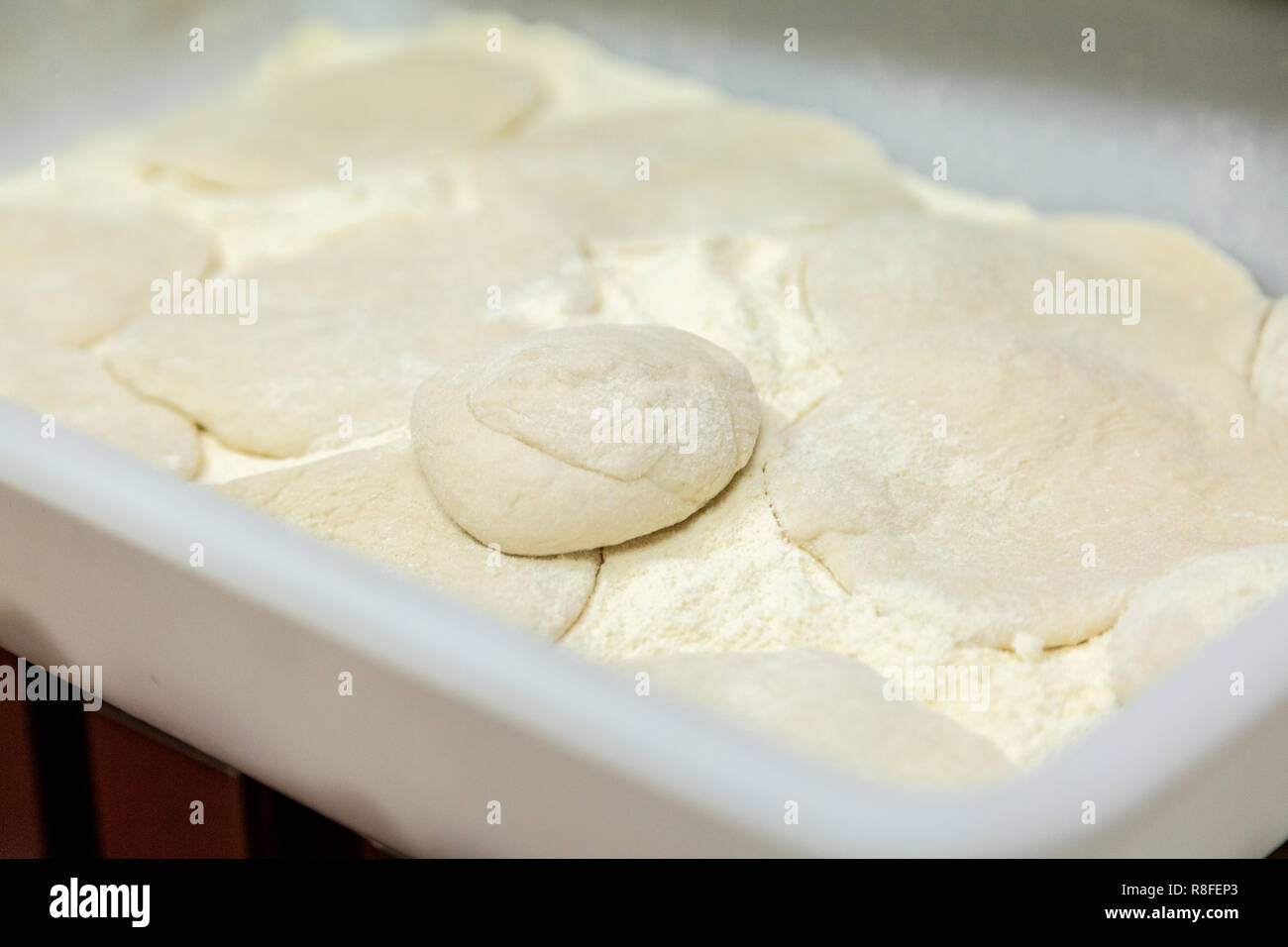 Close up of a tray in a restaurant kitchen with raw round mass with ...