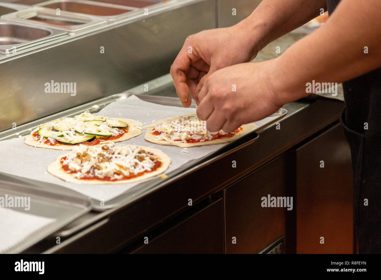 Close up of chef hands adding ingredients on a pizza on a restaurant ...