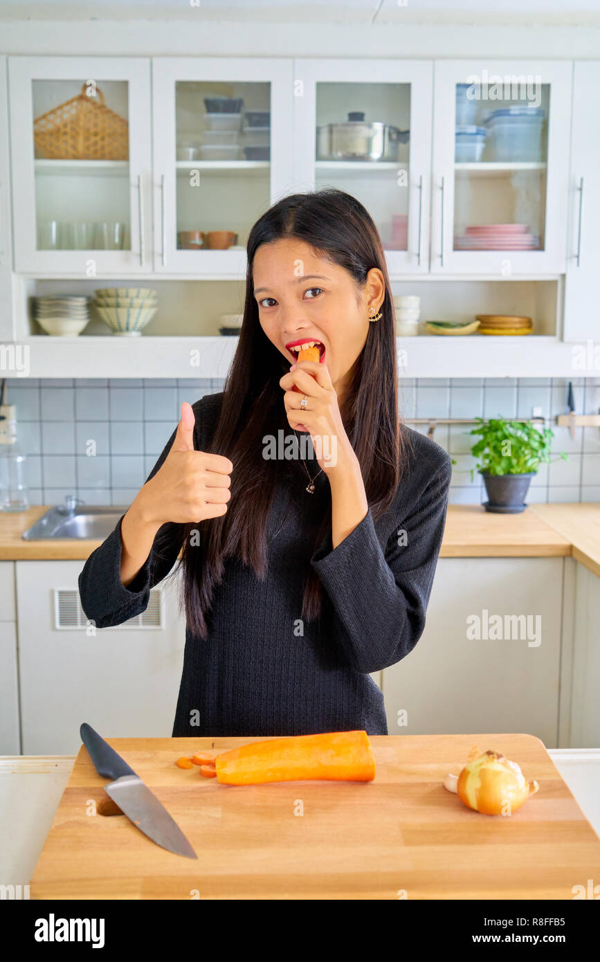 Beautiful woman posing - standing, thumbs up and eating Stock Photo - Alamy