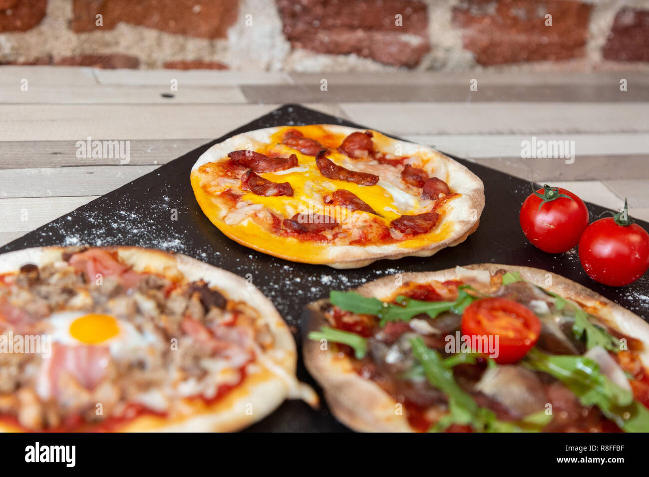 three different pizzas on a black board garnish with flour and two ...