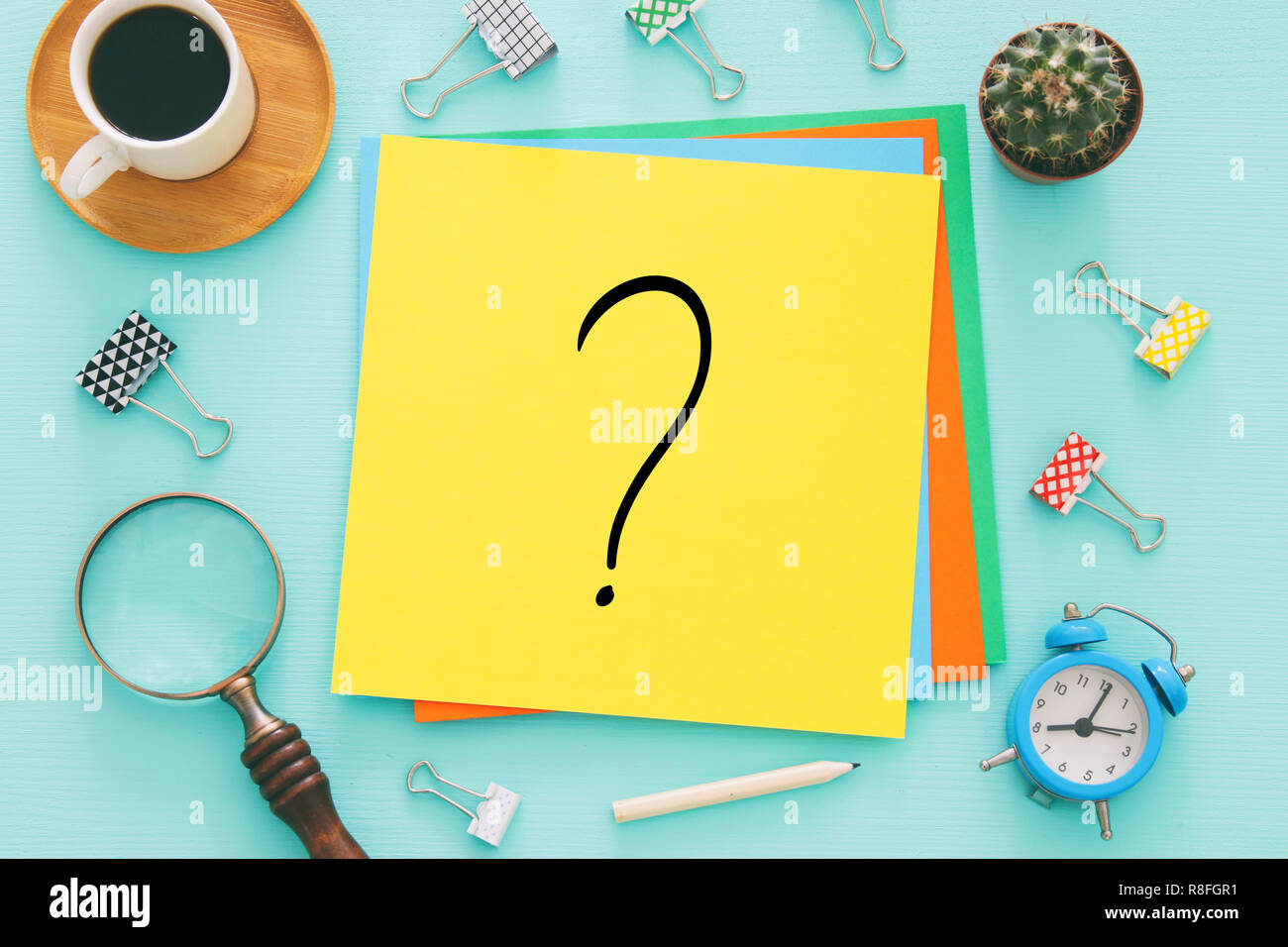 Question mark over yellow paper on office table. Searching for solution ...