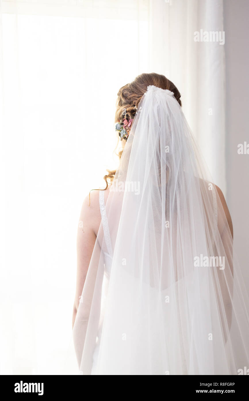 a bride on her back with white veil and dress and a flowers on her ...