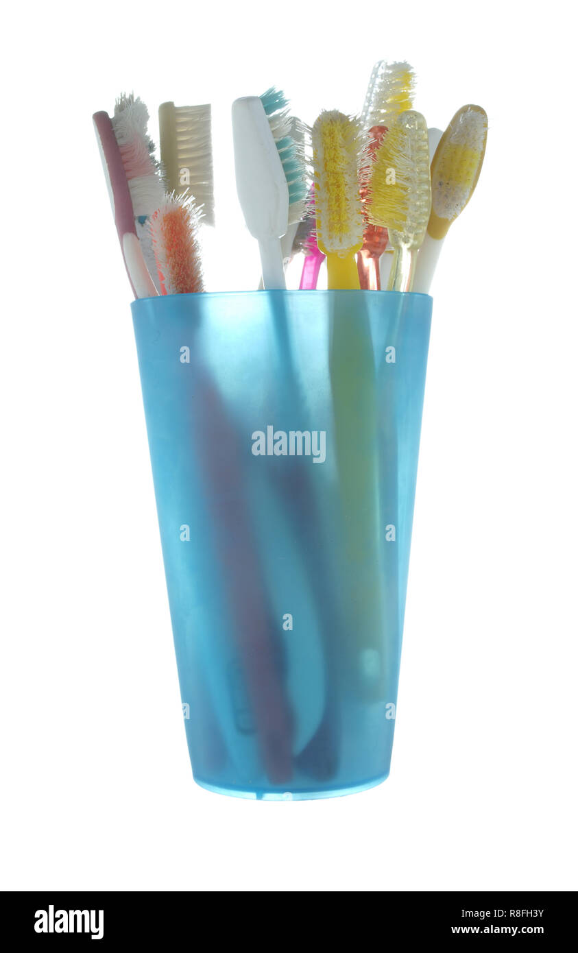 Variety of toothbrushes in a plastic glass isolated on white background ...