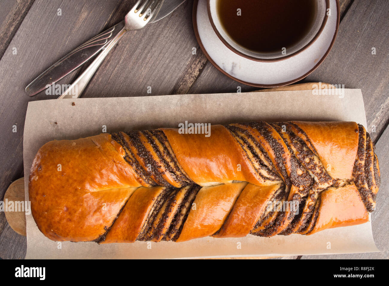 Overhead view of poppy roll with tea over wooden background Stock Photo ...