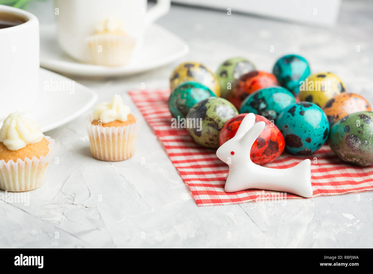 Easter morning concept with white hare in focus with eggs, cupcakes and ...