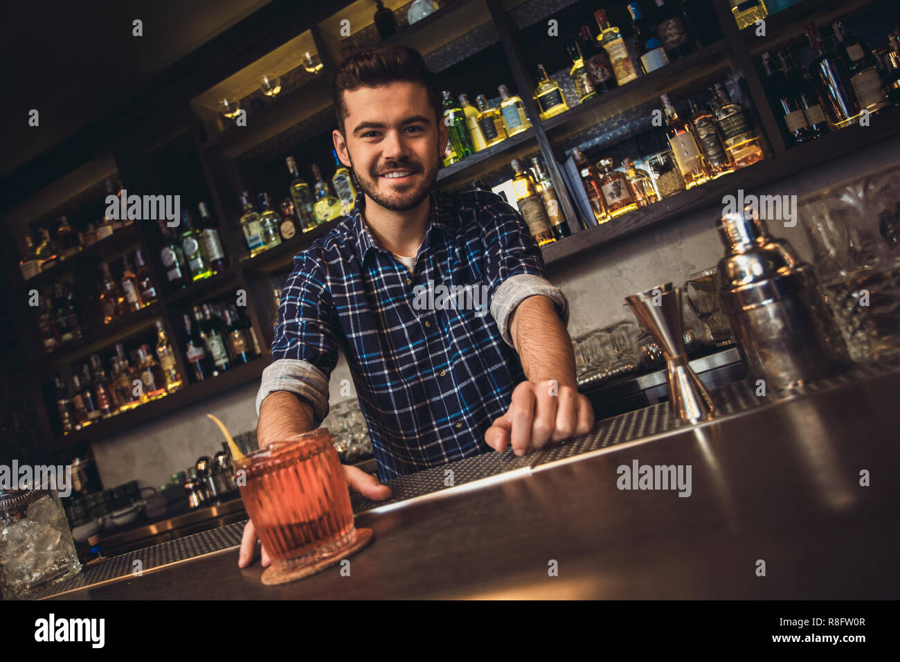 Young bartender standing at bar counter serving cocktail cheerful Stock ...