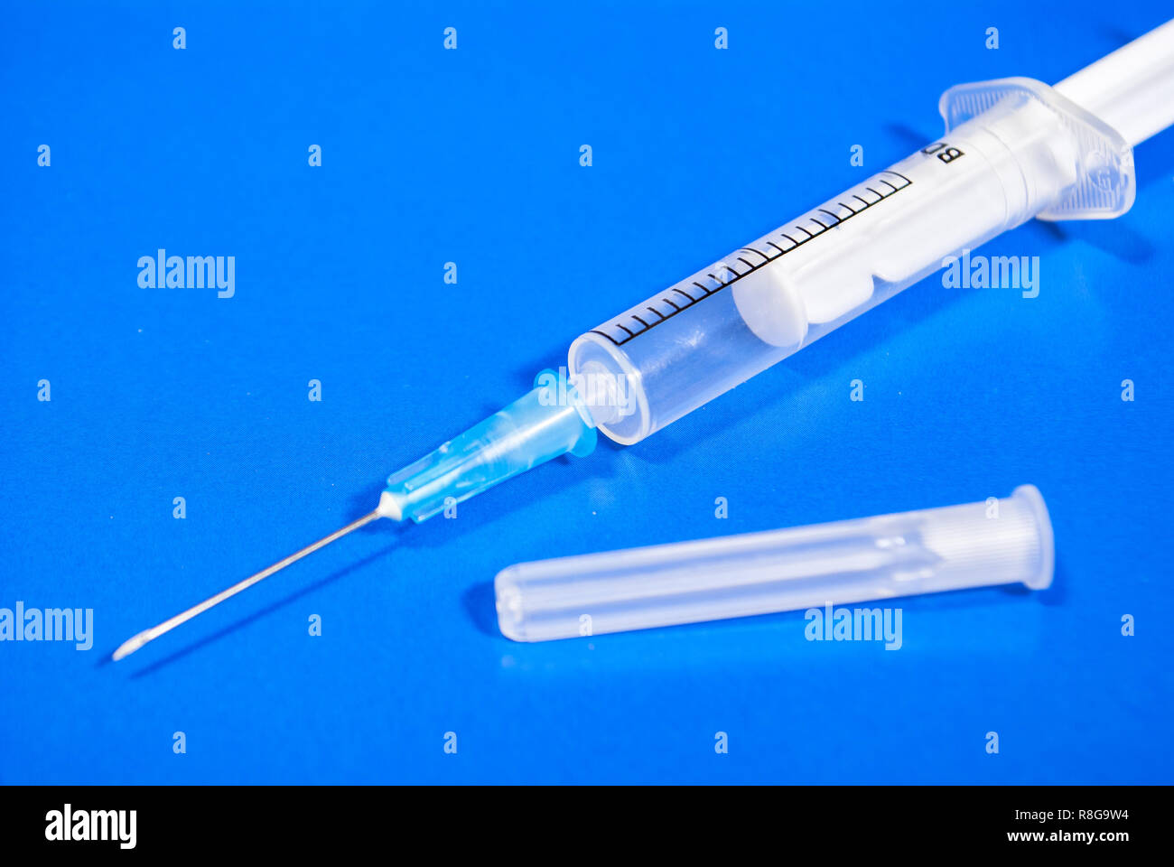 classic transparent medical syringe with a needle on a blue background ...