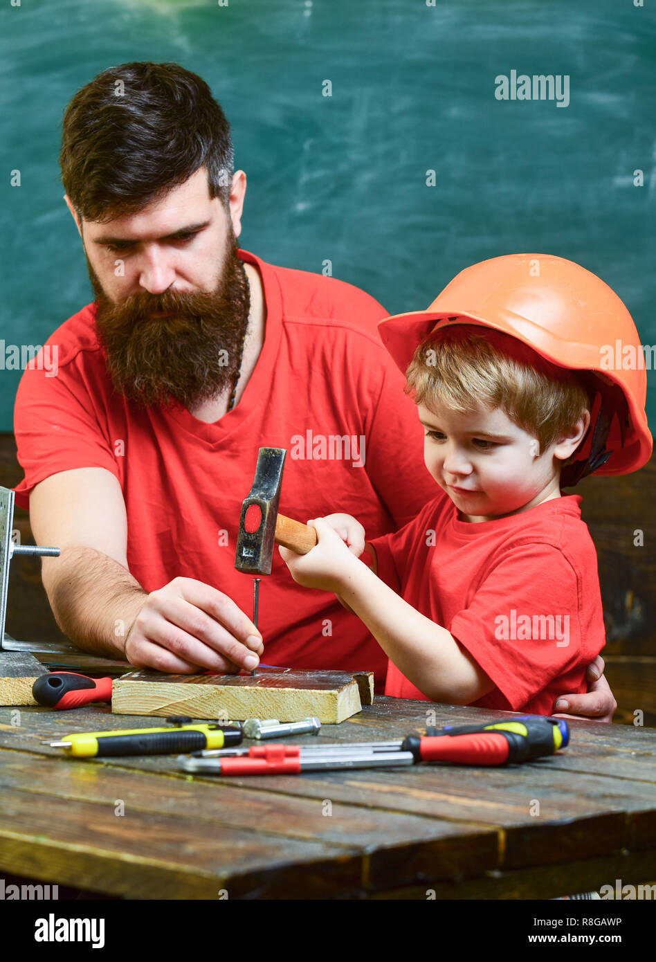 Father with beard teaching little son to use tools, hammering ...