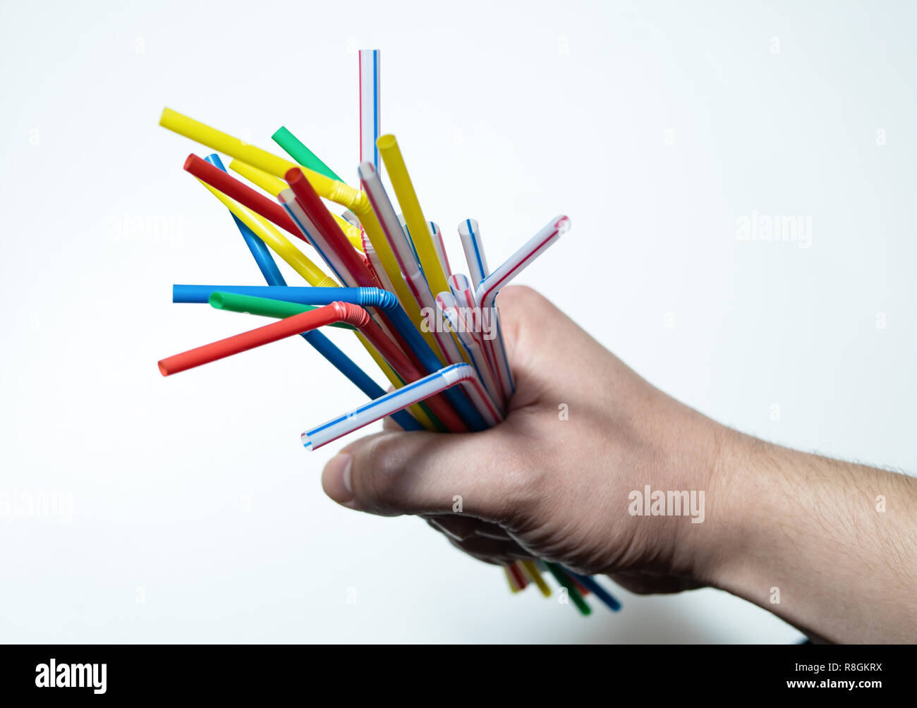 hand holding a bunch of vibrant drinking straws on white background ...