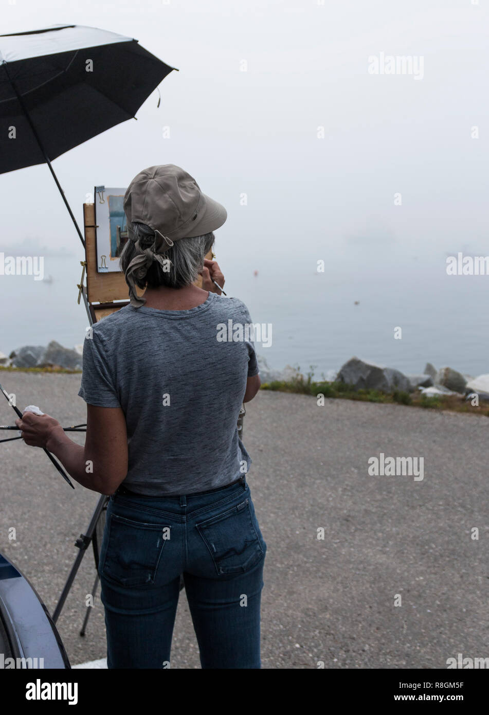 A female artist is standing in a parking lot with an unbrella ...