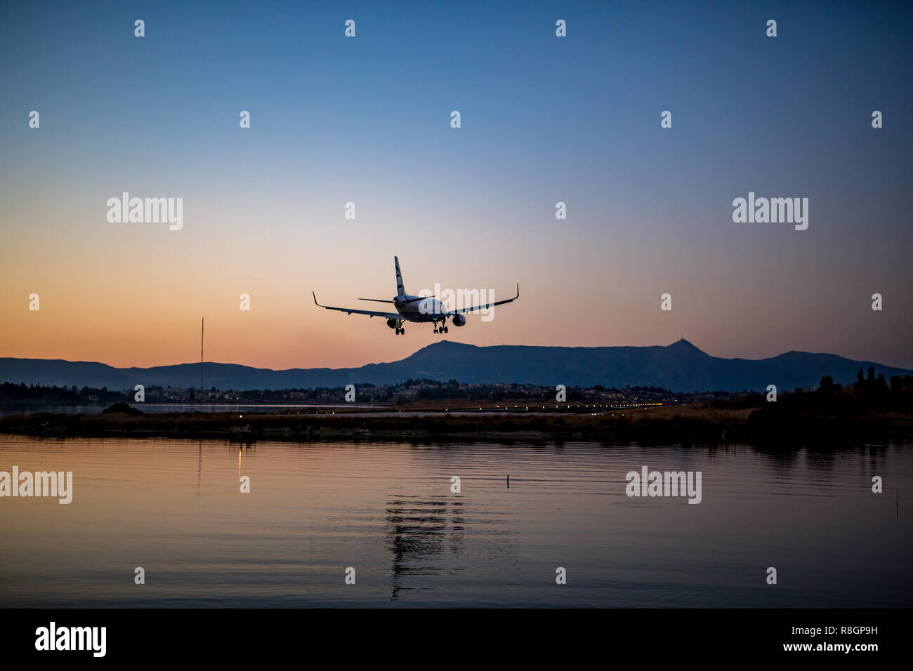 Passenger airplane is landing at Corfu airport at sunset, the golden ...