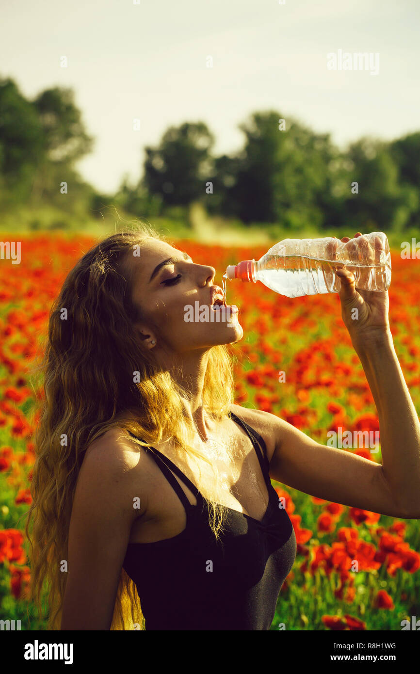 woman in field of poppy seed drink water from bottle Stock Photo - Alamy