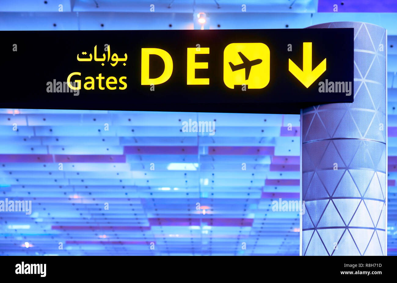 English and Arabian yellow illuminated sign at airport with gate ...