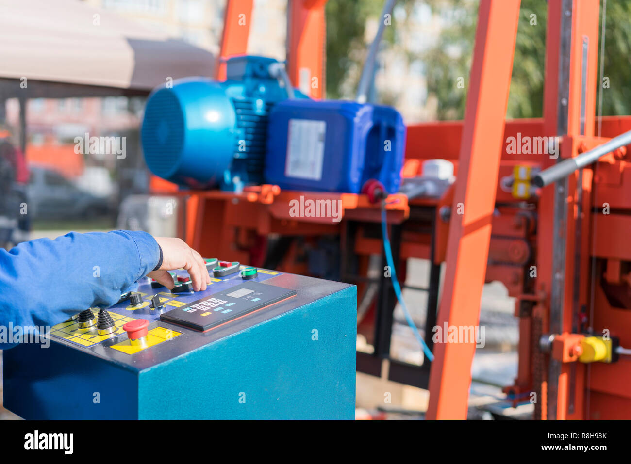 Worker pressing buttons on CNC machine control board in factory. Worker ...