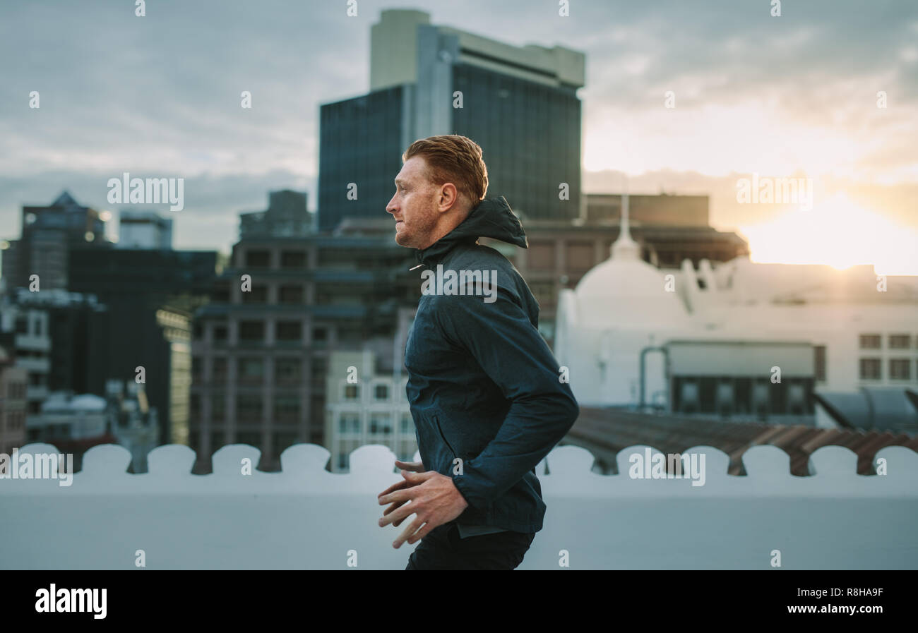 fitness man doing exercises on the terrace of a building with sunrise ...