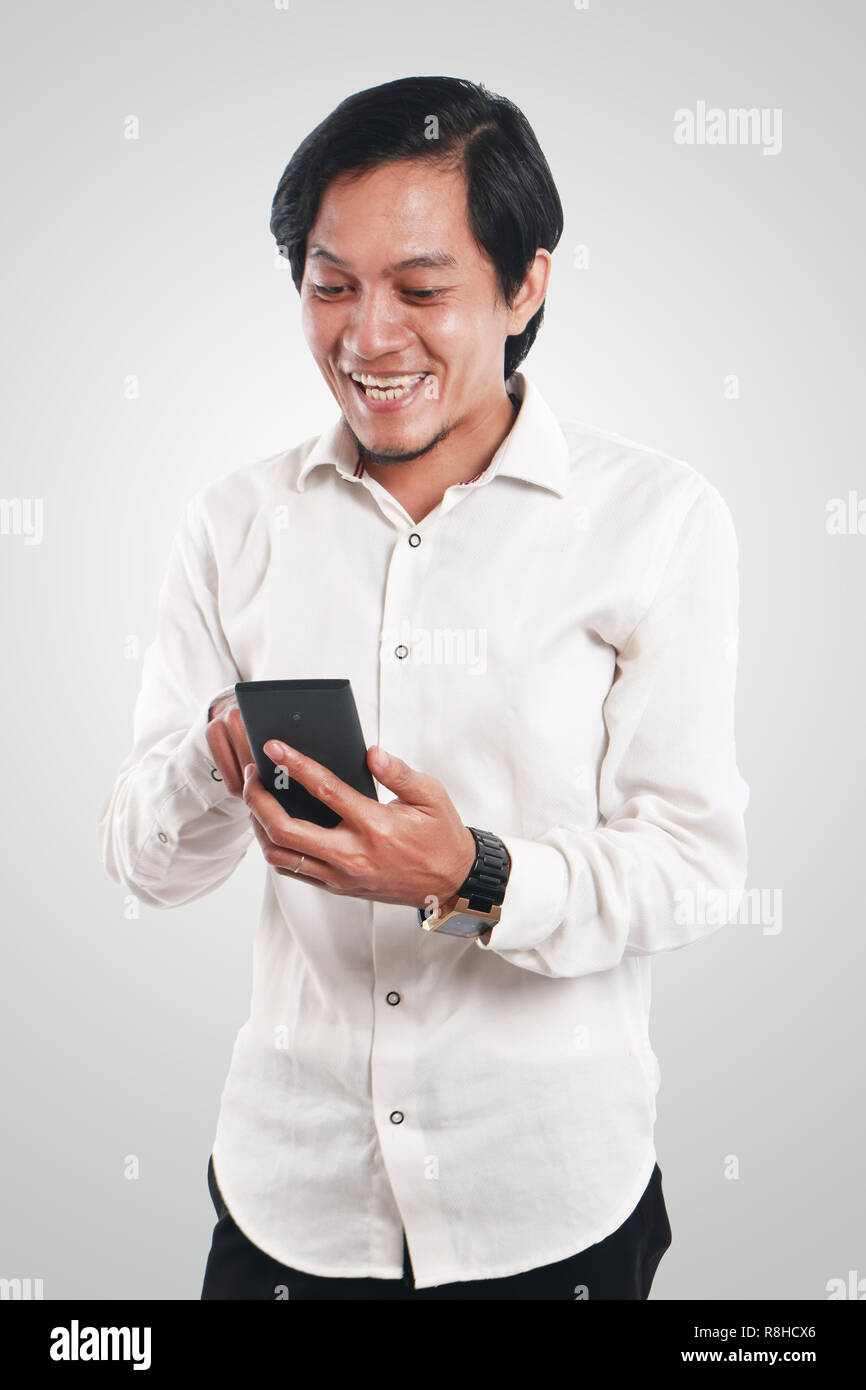 Photo image portrait of a funny young Asian man smiling while texting ...