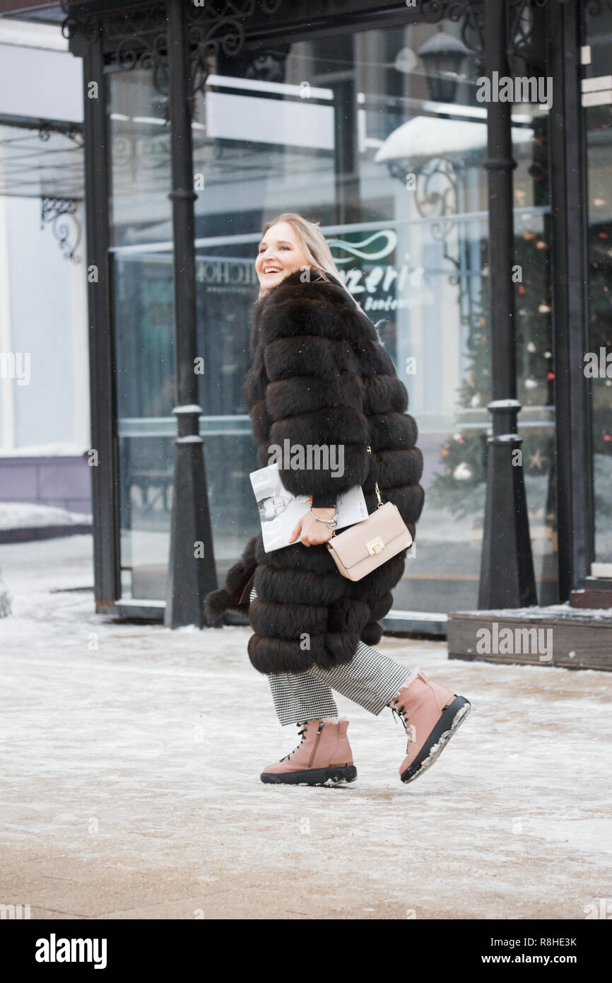 girl walking on a snow in the city street on curb covered with snow ...