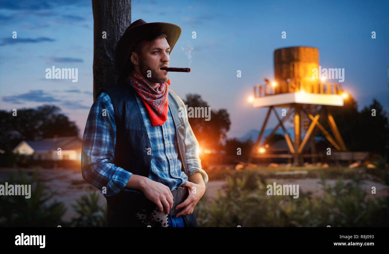 Brutal cowboy smokes a cigar on sunset, evening relax on texas ranch ...