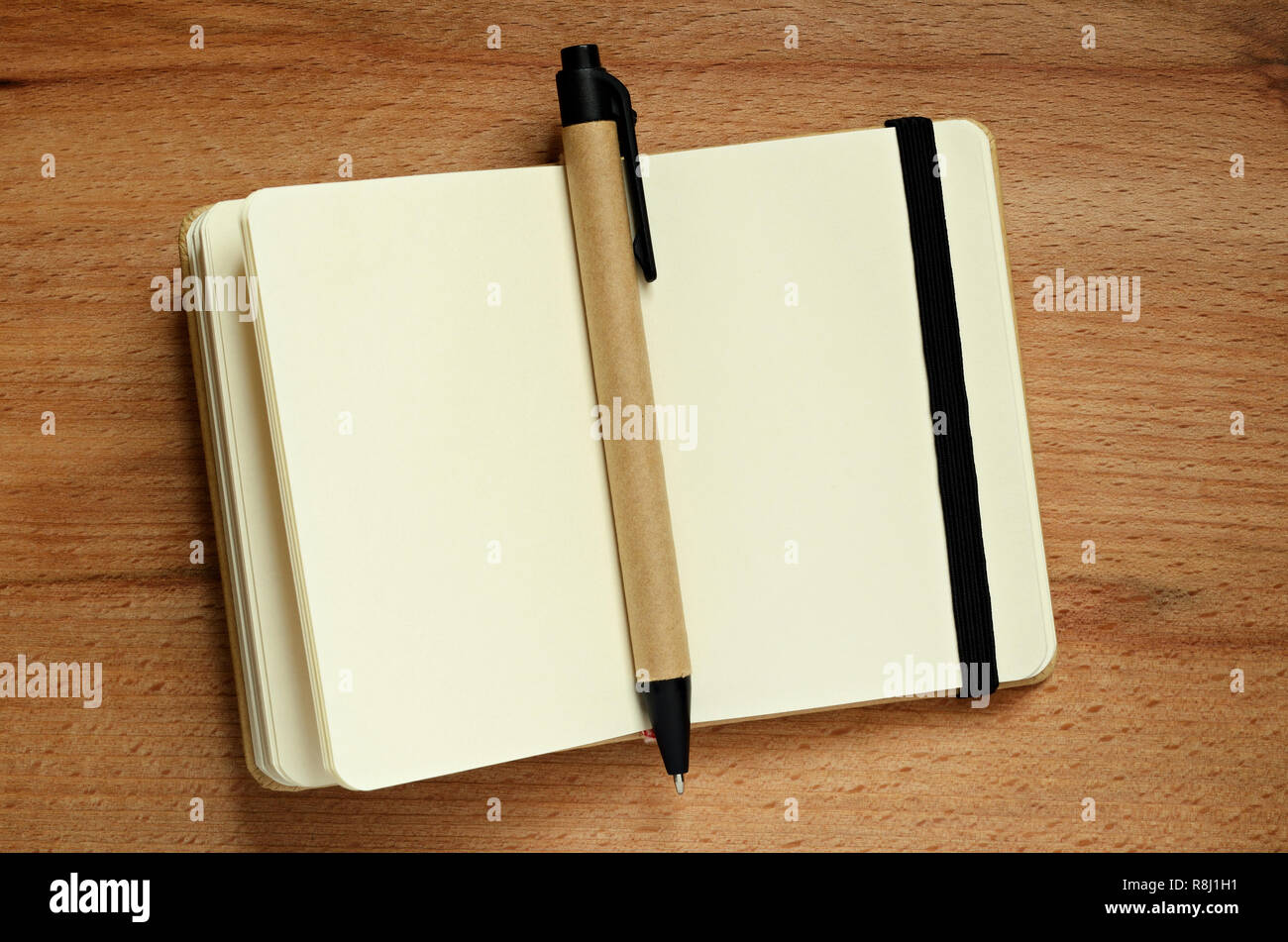 Closed notebook and a pen on wooden desk Stock Photo - Alamy