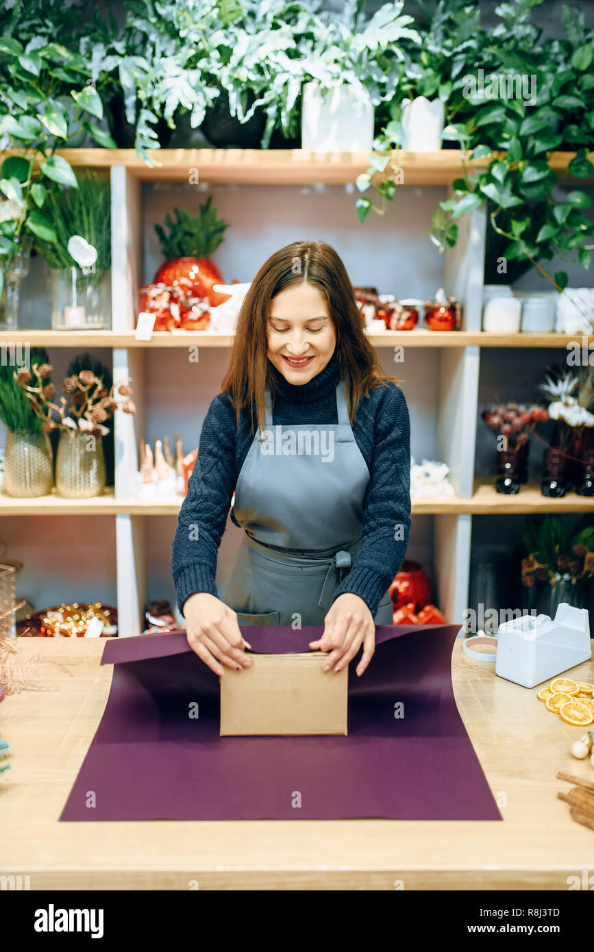Female seller holds unwrapped carton gift box. Present wrapping papaer ...