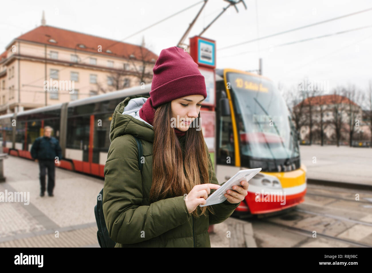 A girl or a tourist got off the tram stop from a tram and looks at a ...