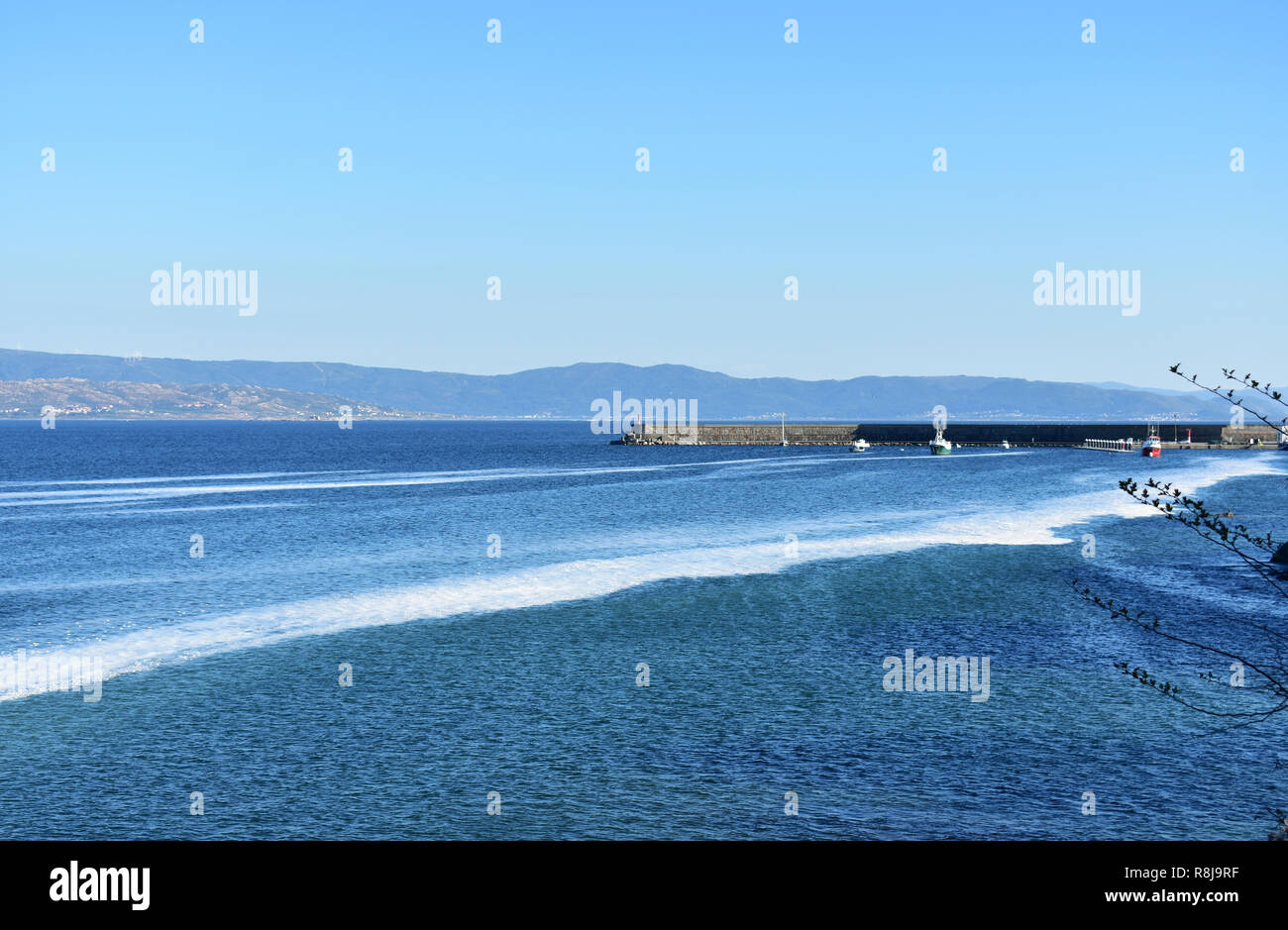Harbour with fishing boats in a bay. Blue sea with foam, clear sky ...
