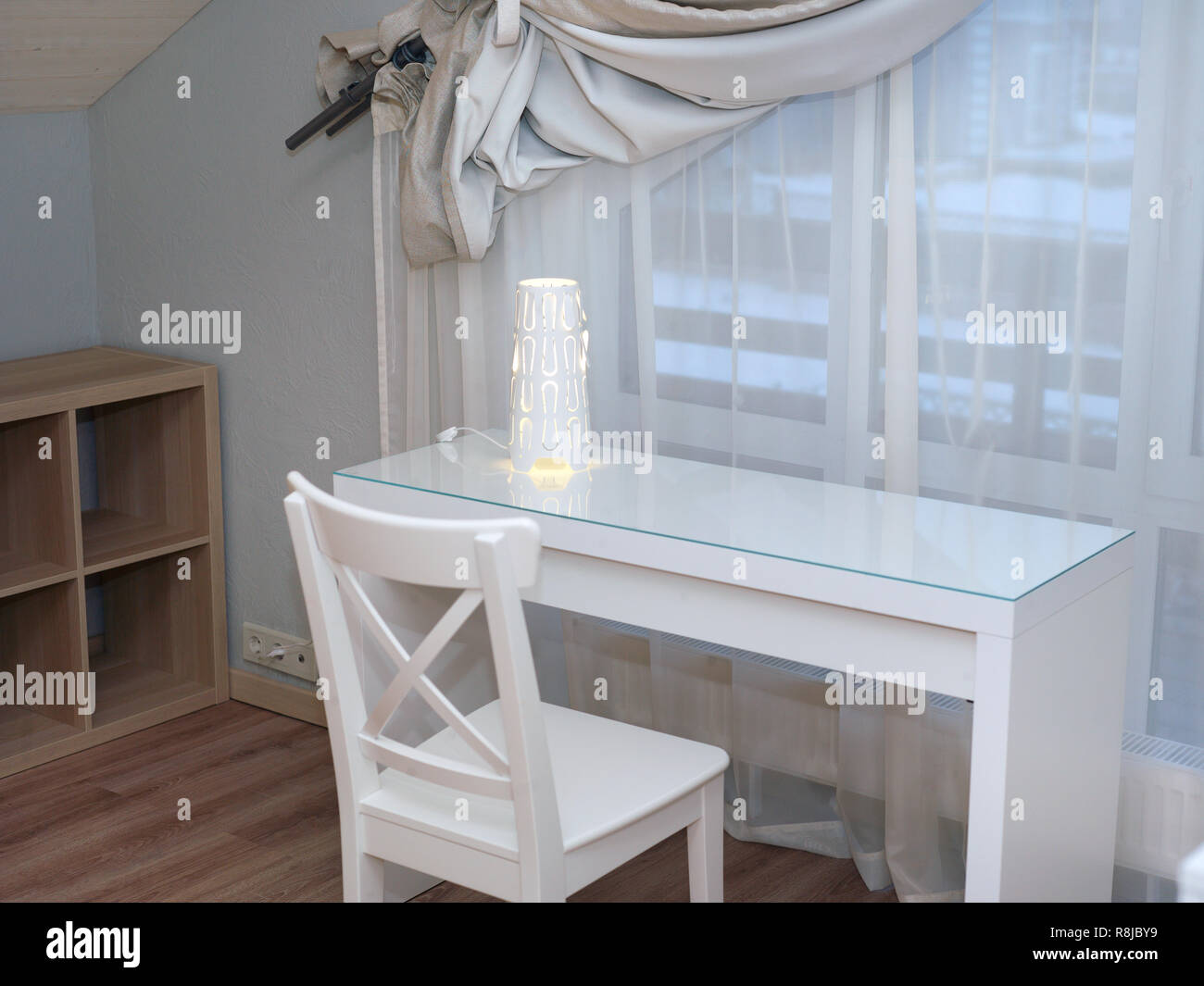 White table and room in front of the window with a half shut curtain ...