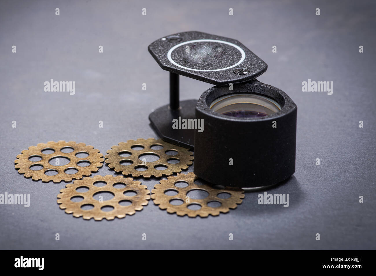 Loupe, magnifying glass and old vintage antique hour metal gears ...