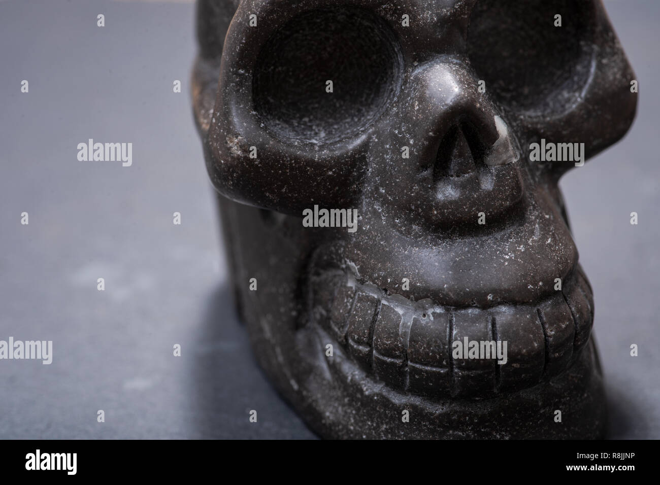 Grey volcanic rock carved skull on natural stone background Stock Photo ...
