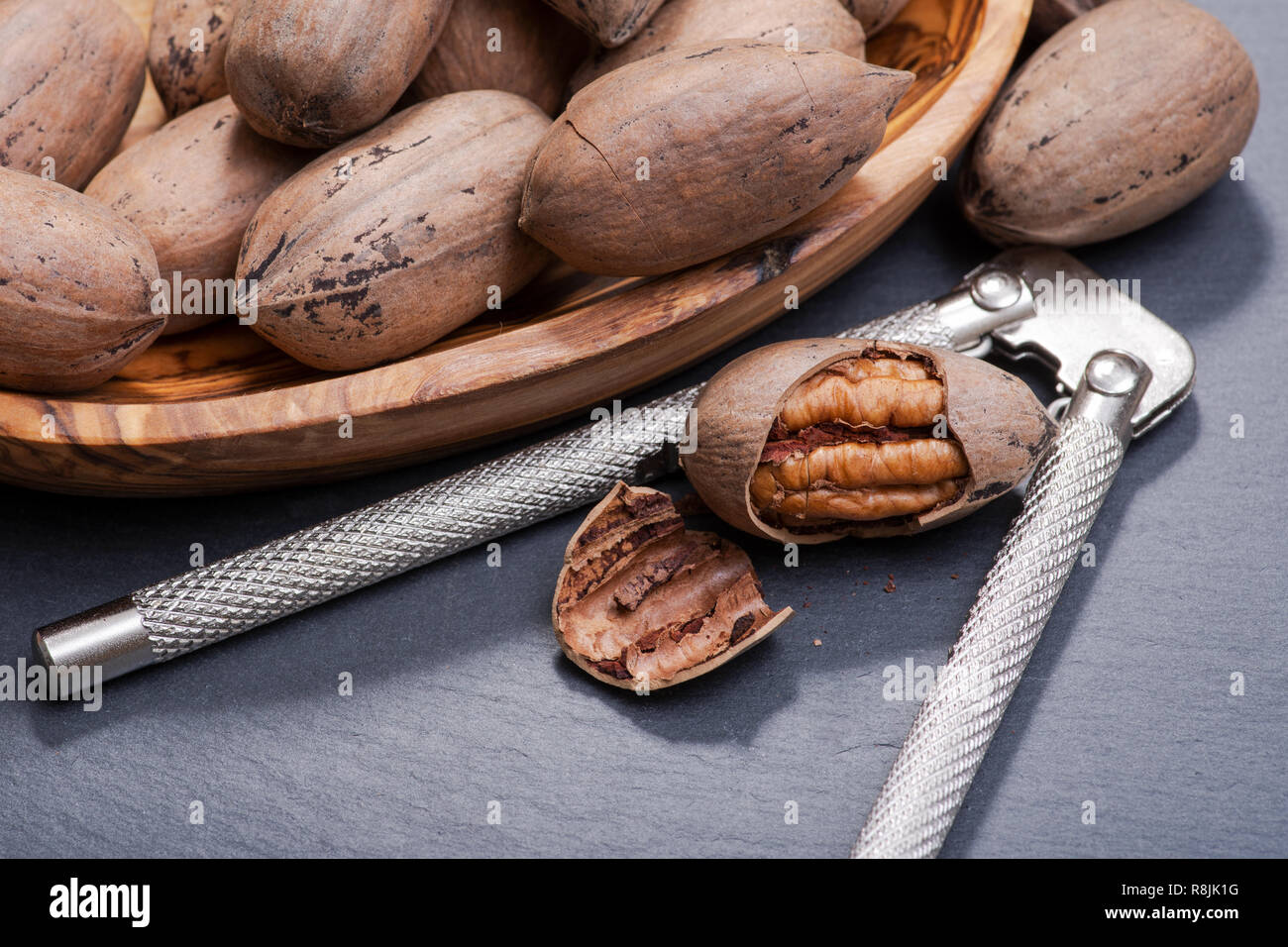Fresh organic pecans nuts and stainless steel nutcracker on natural ...