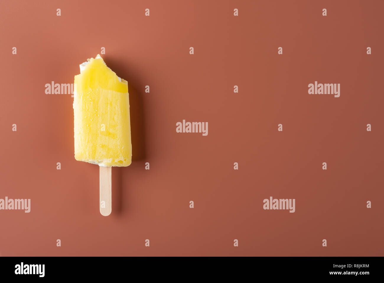 yellow popsicle with some bites on a chocolate brown background Stock ...