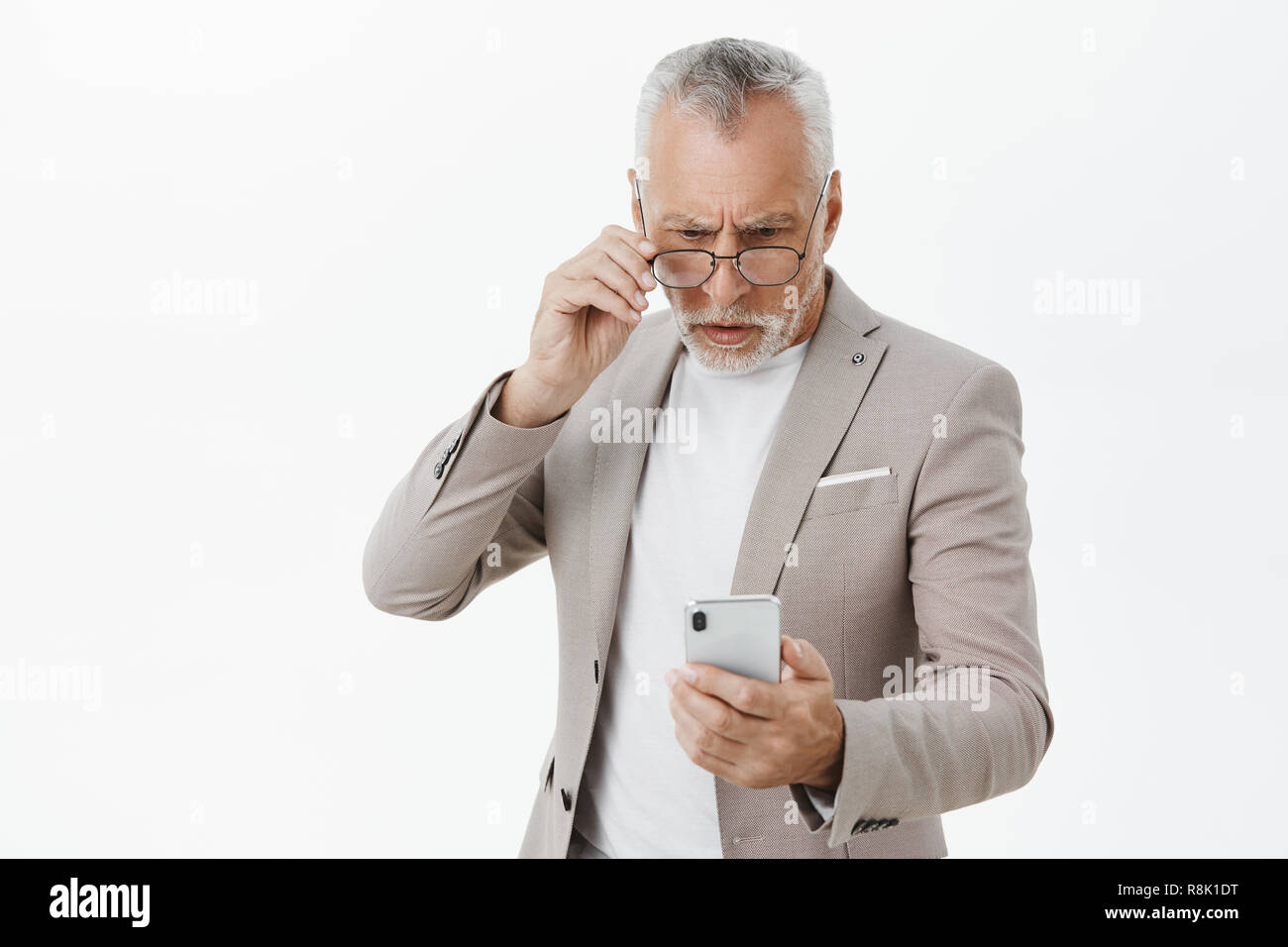 Portrait of confused old man trying understand how use new smartphone ...