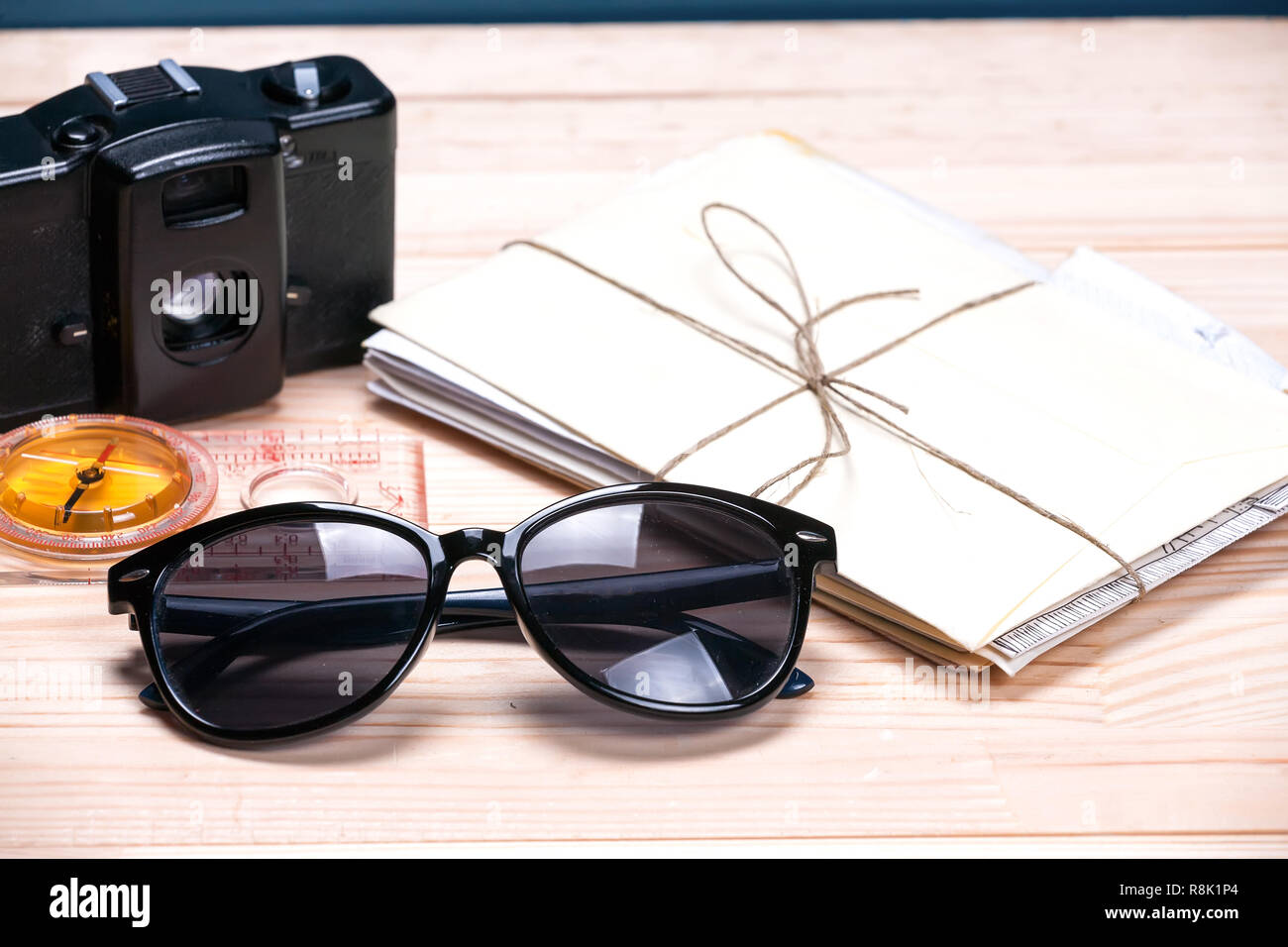Sunglasses, compass, old film camera and a bunch of letters on a light ...
