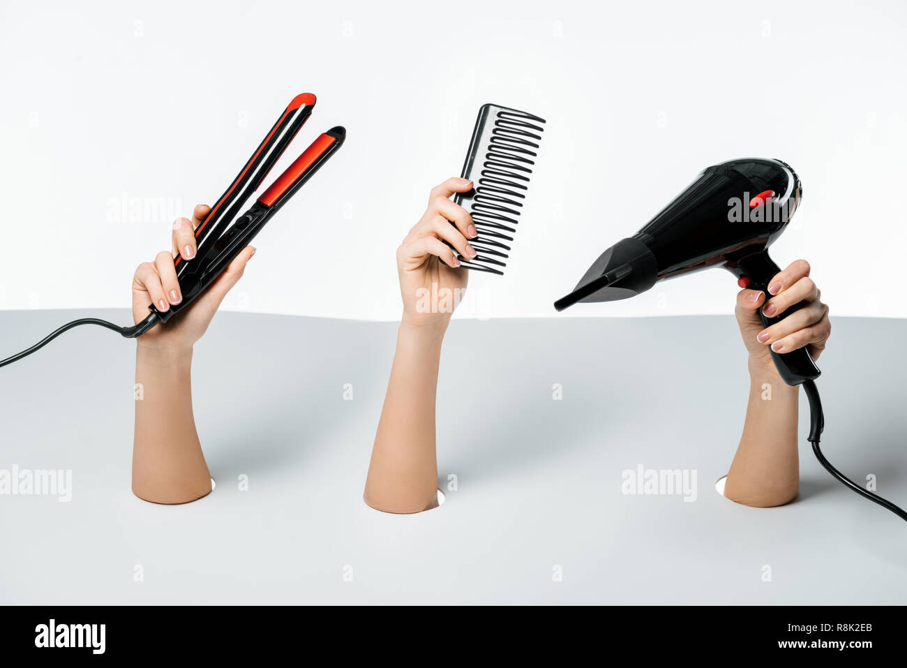 partial view of female hands holding hairstyle tools through holes on ...