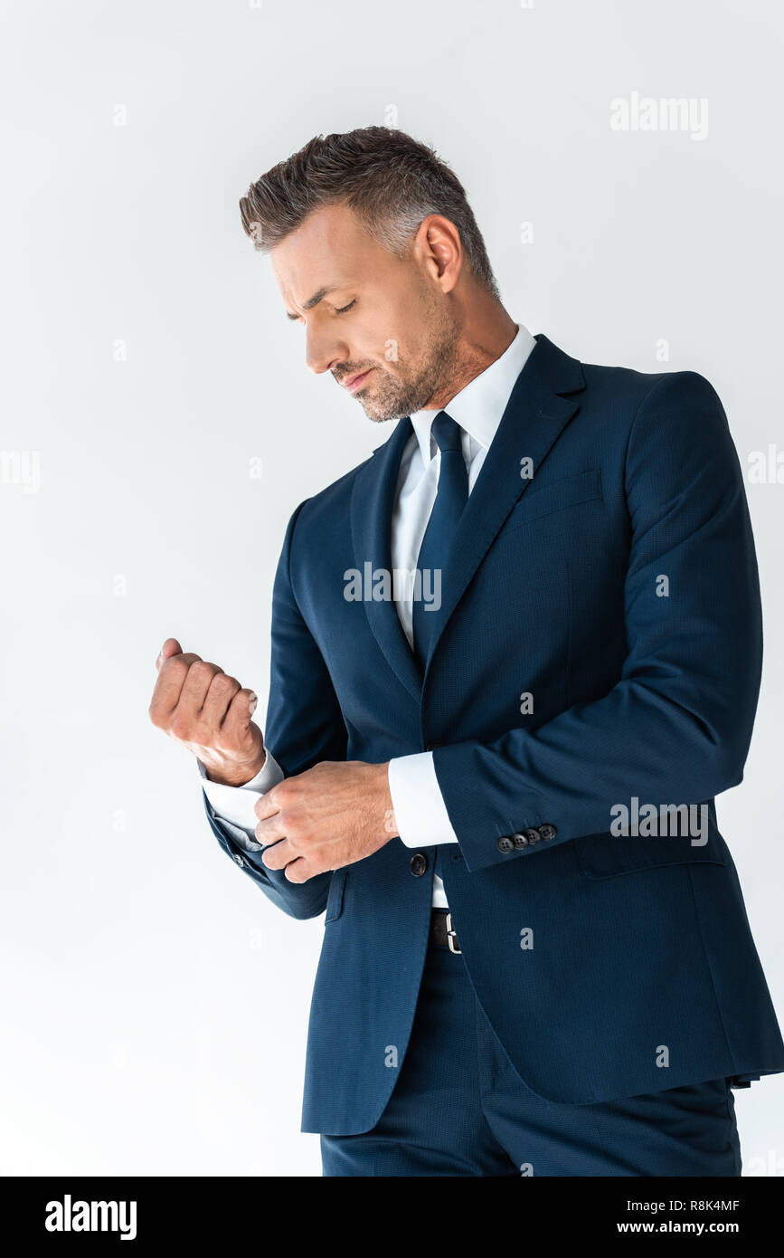 low angle view of handsome businessman buttoning cuff isolated on white ...