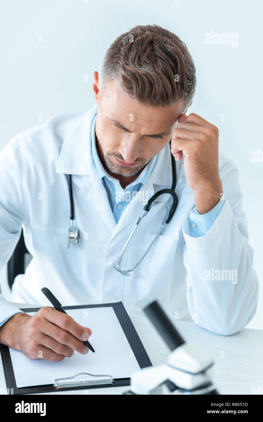 pensive handsome scientist writing something to clipboard isolated on ...