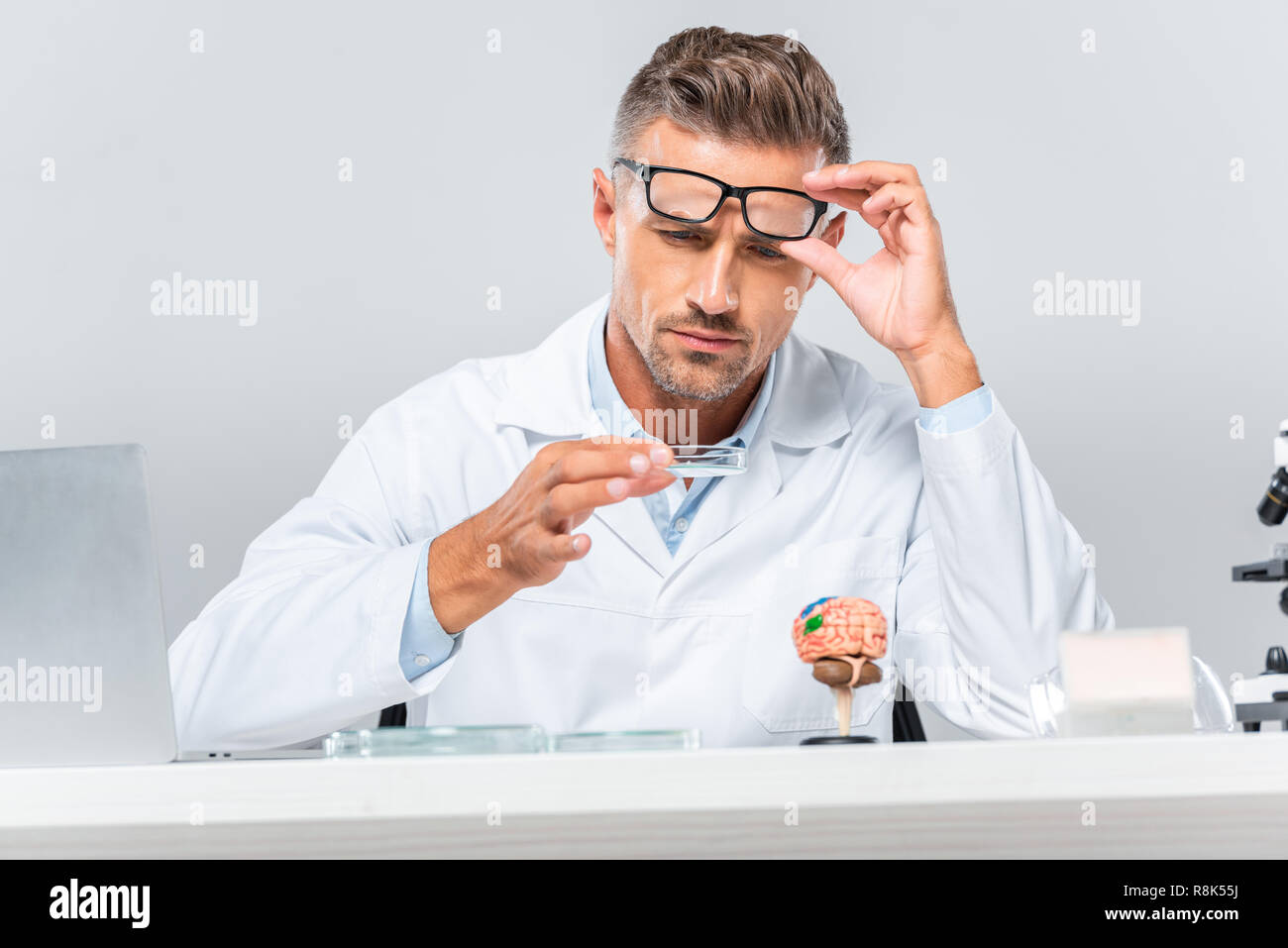 surface level of handsome scientist looking at reagent at table ...