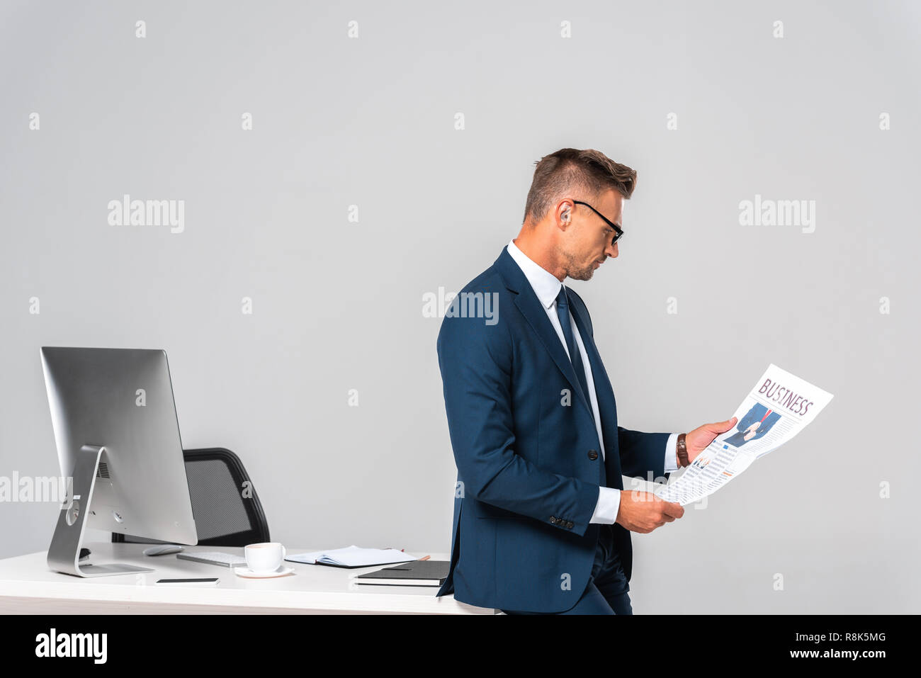 side view of handsome businessman reading newspaper isolated on white ...
