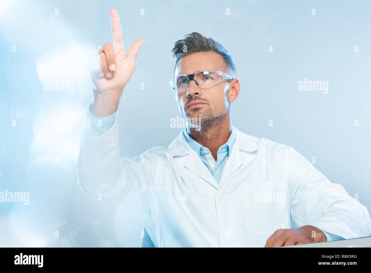 handsome scientist in protective glasses touching something isolated on ...
