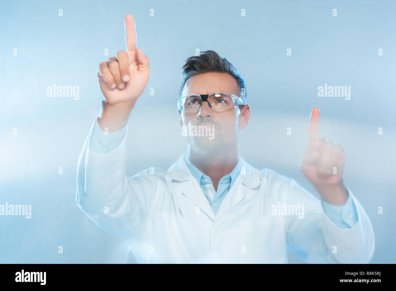 handsome scientist in protective glasses and white coat touching ...