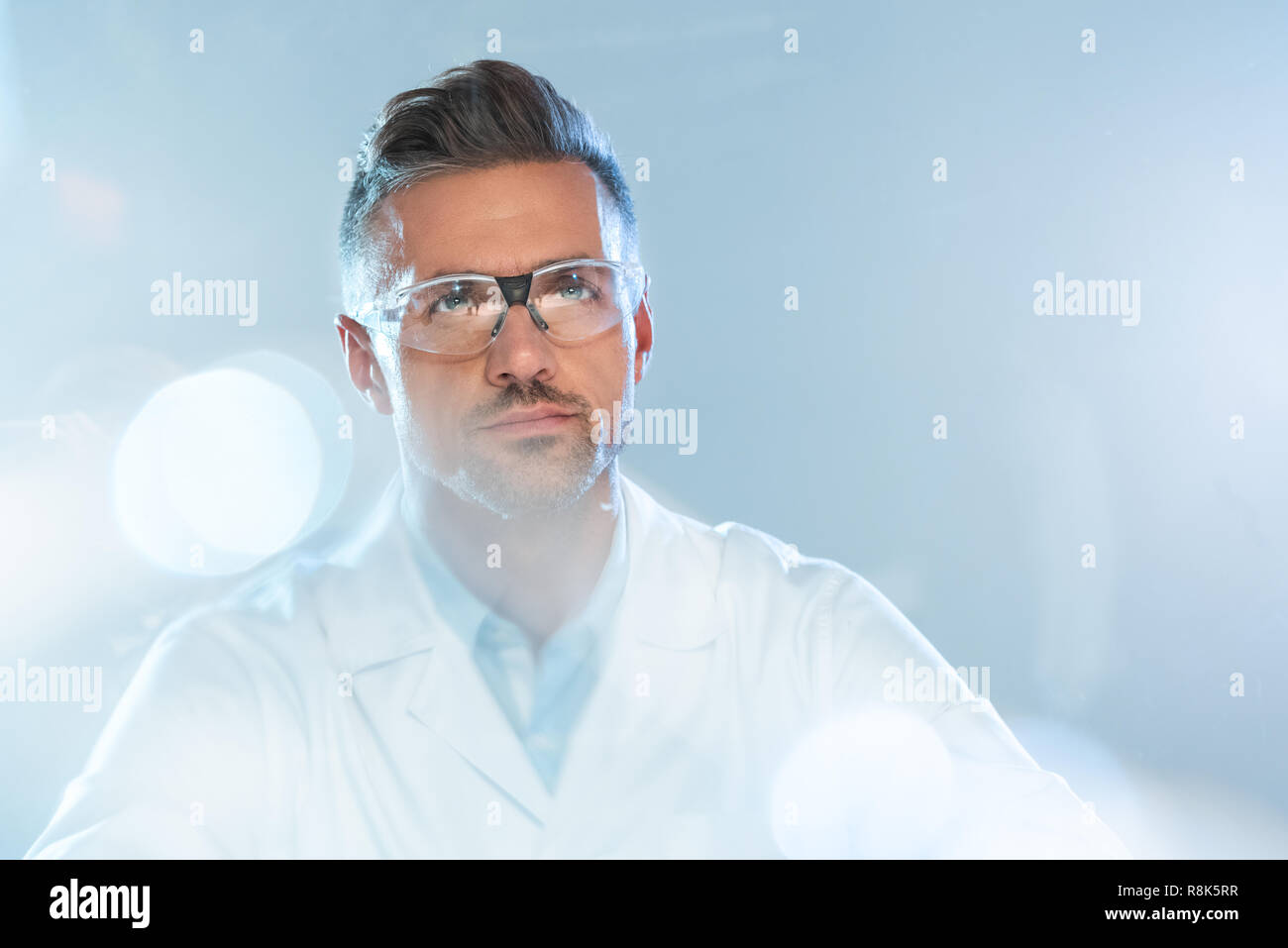 portrait of handsome scientist in protective glasses looking up ...