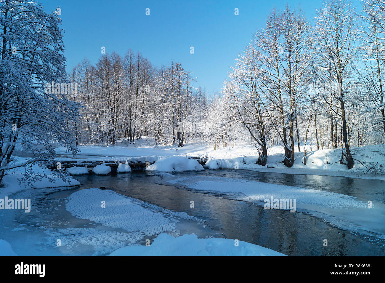 Winter landscape with stream and footbridge in rural terrain on ...