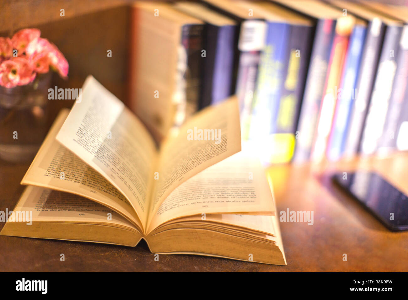 an open book with open pages and mobile phone and flower and books in ...