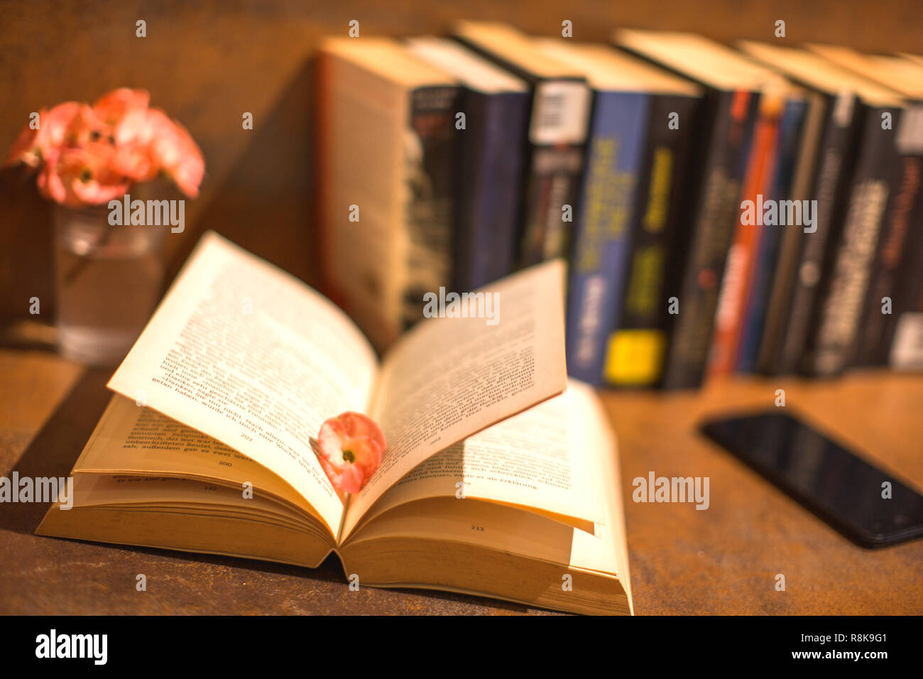 an open book with open pages and mobile phone and flower and books in ...