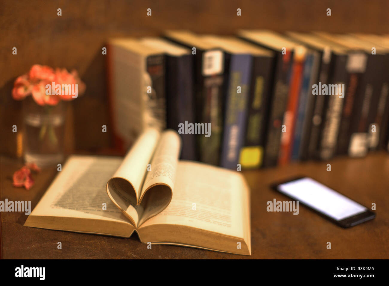 an open book with pages heart silhouette and mobile phone and flower ...