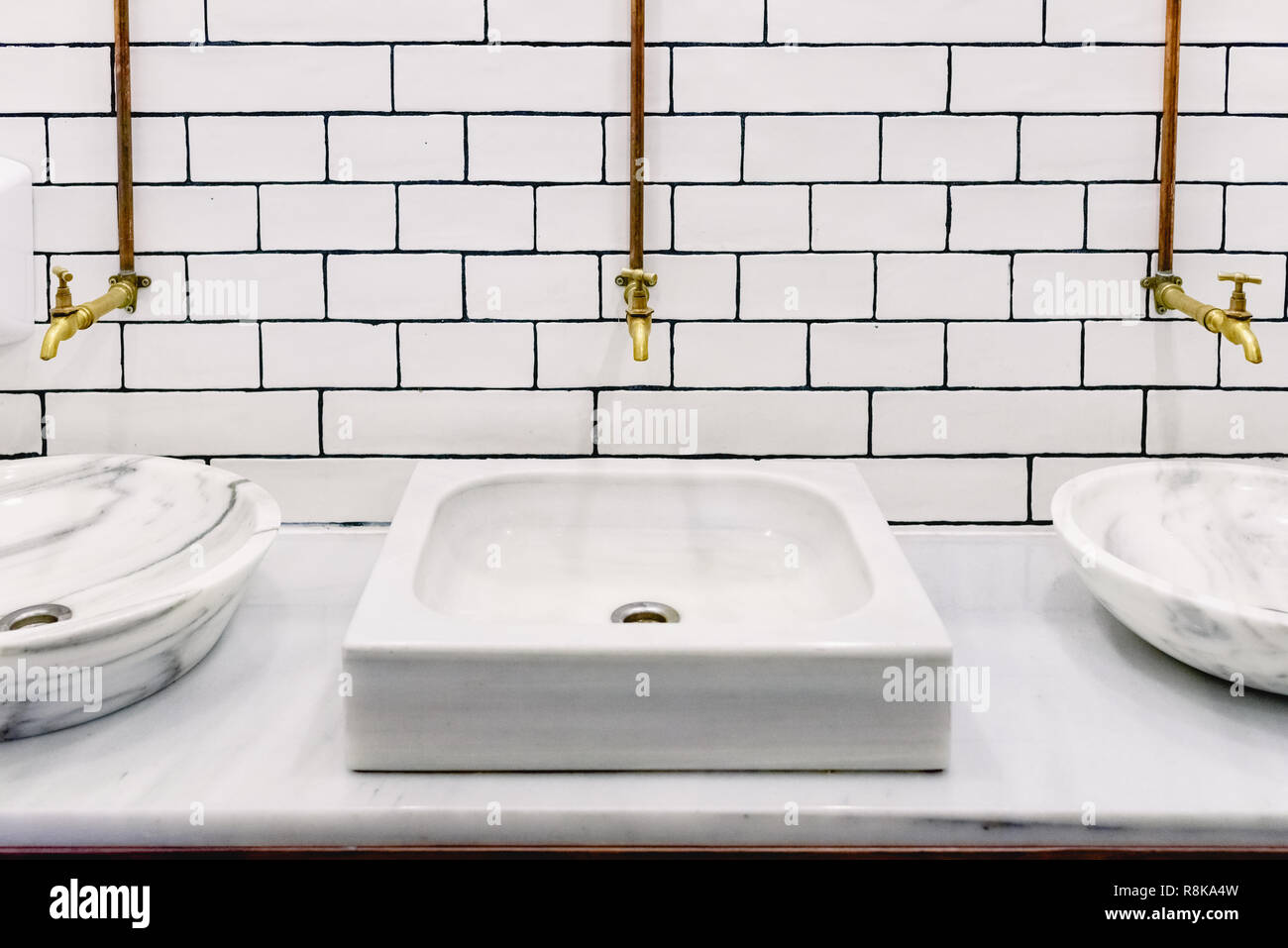 Marble sink in a public restroom with retro golden water tap with ...